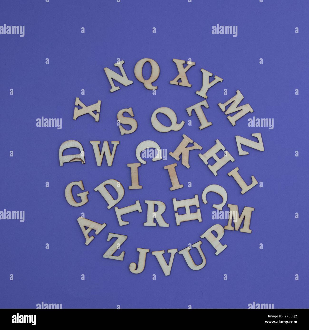Various wooden letters of the alphabet arranged in a circle on a purple ...