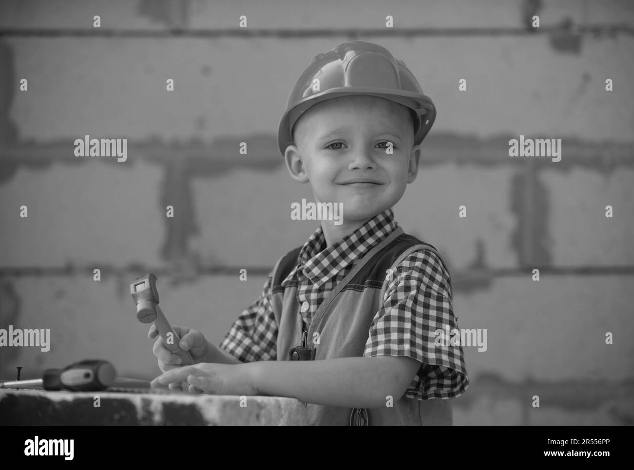 Child play with supplies, tools saw, hammer, screwdriver, helmet ...