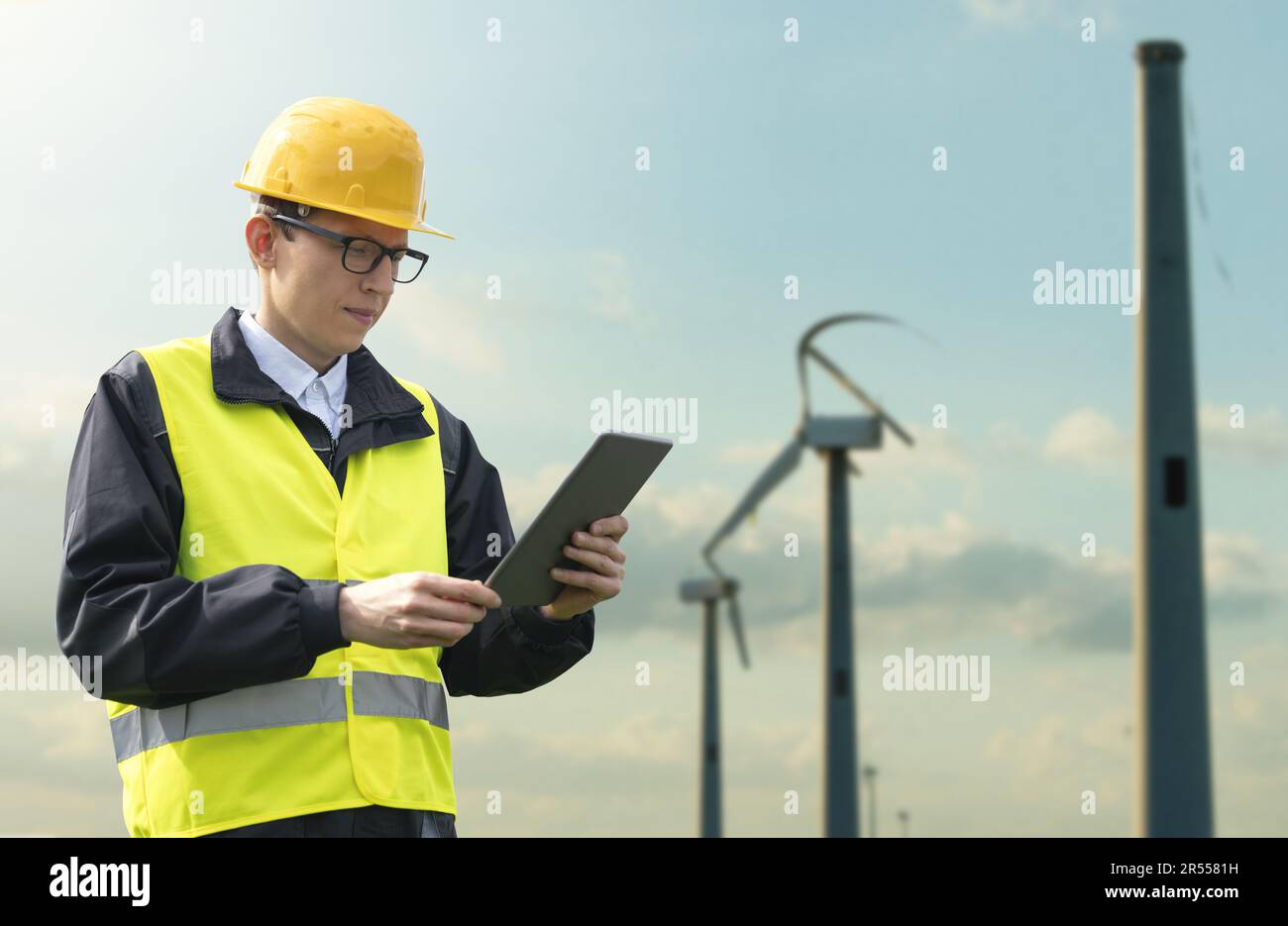 Engineer with tablet computer on a background of broken wind turbine ...