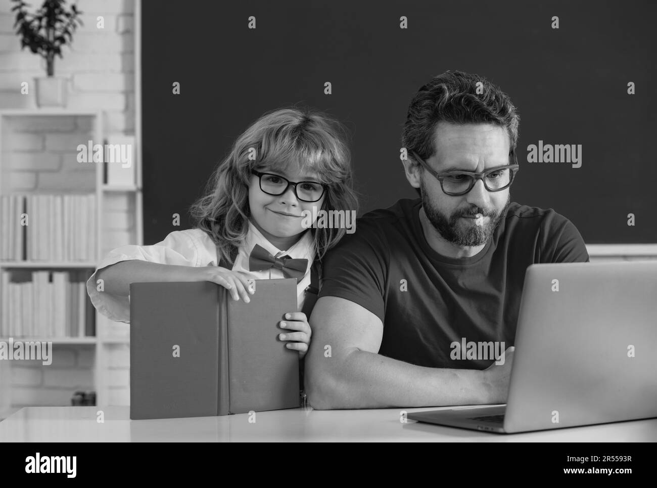 Teacher helping child student pupil from elementary school in classroom. Teacher and pupil boy ...