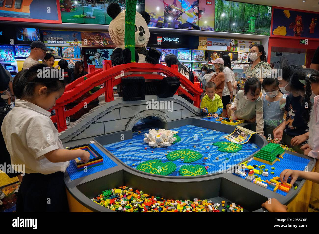 Children play with Lego blocks near a panda made of Lego at a retail ...