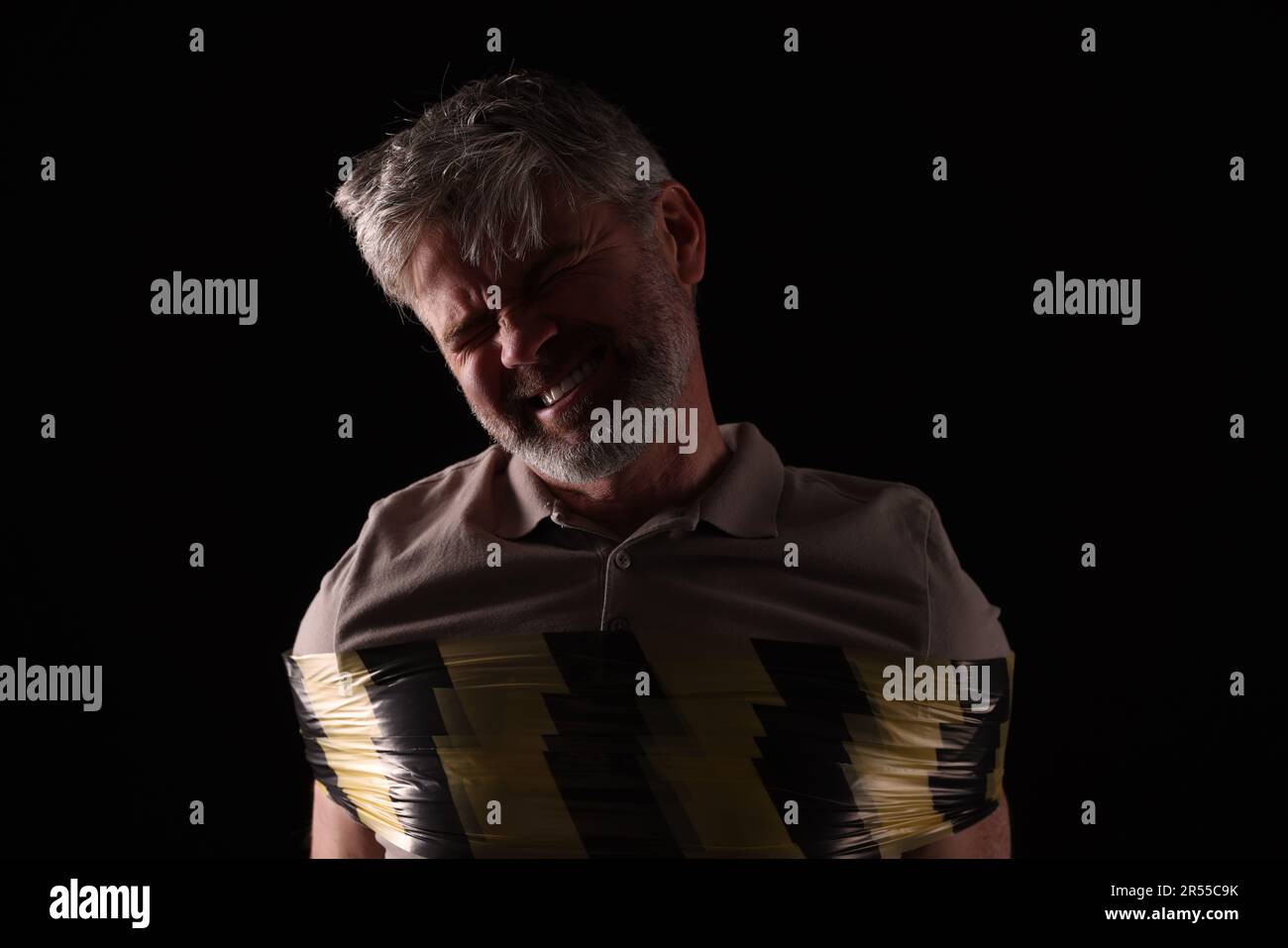 Emotional victim tied with duct tape on black background. Hostage ...