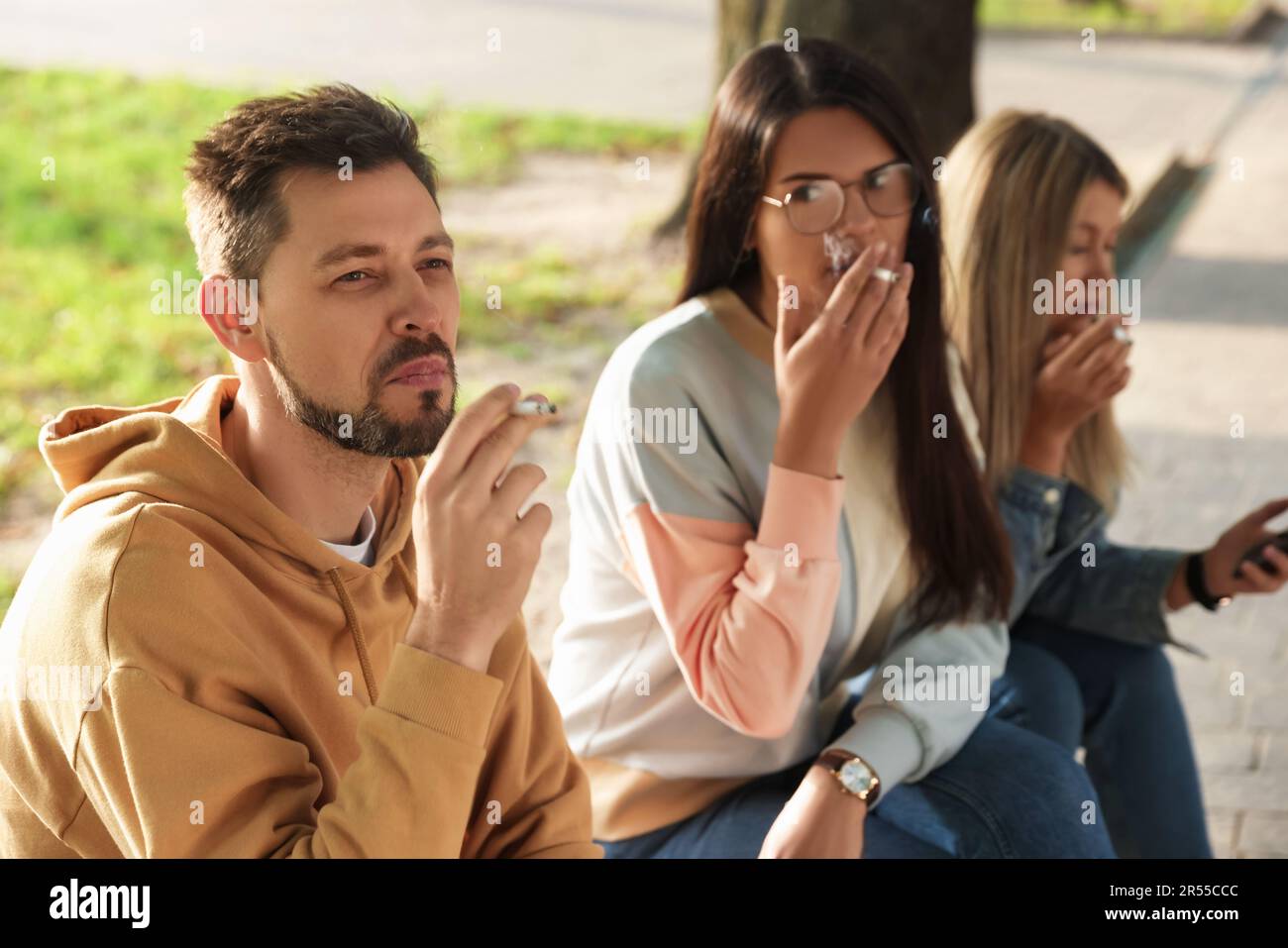 People smoking cigarettes outdoors on sunny day Stock Photo - Alamy