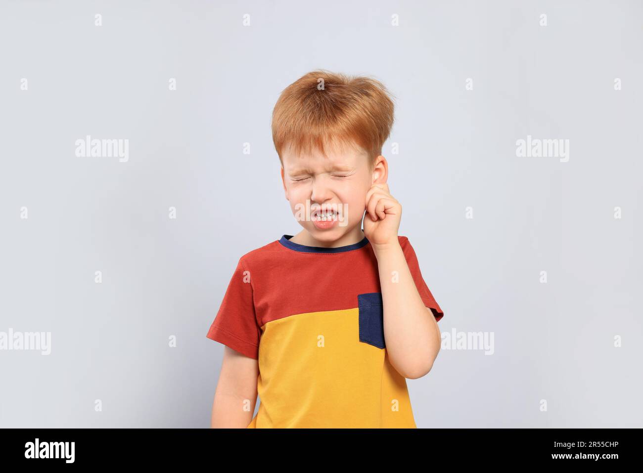 Little boy suffering from ear pain on light grey background Stock Photo ...