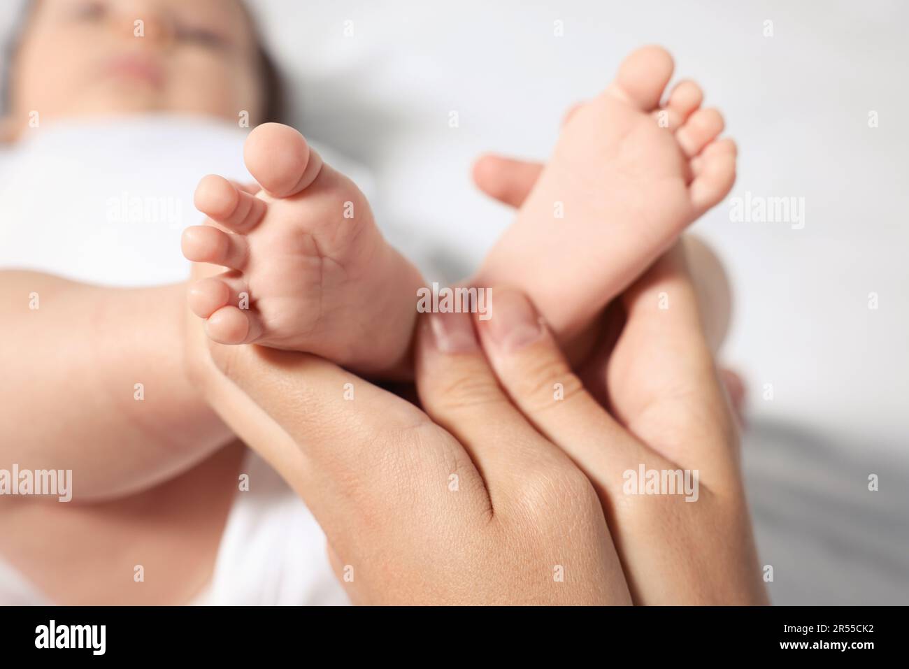 Mother holding legs of her little baby on bed, closeup Stock Photo - Alamy