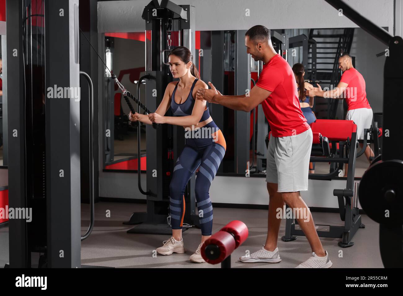 Trainer explaining woman how to do exercise properly in modern gym ...