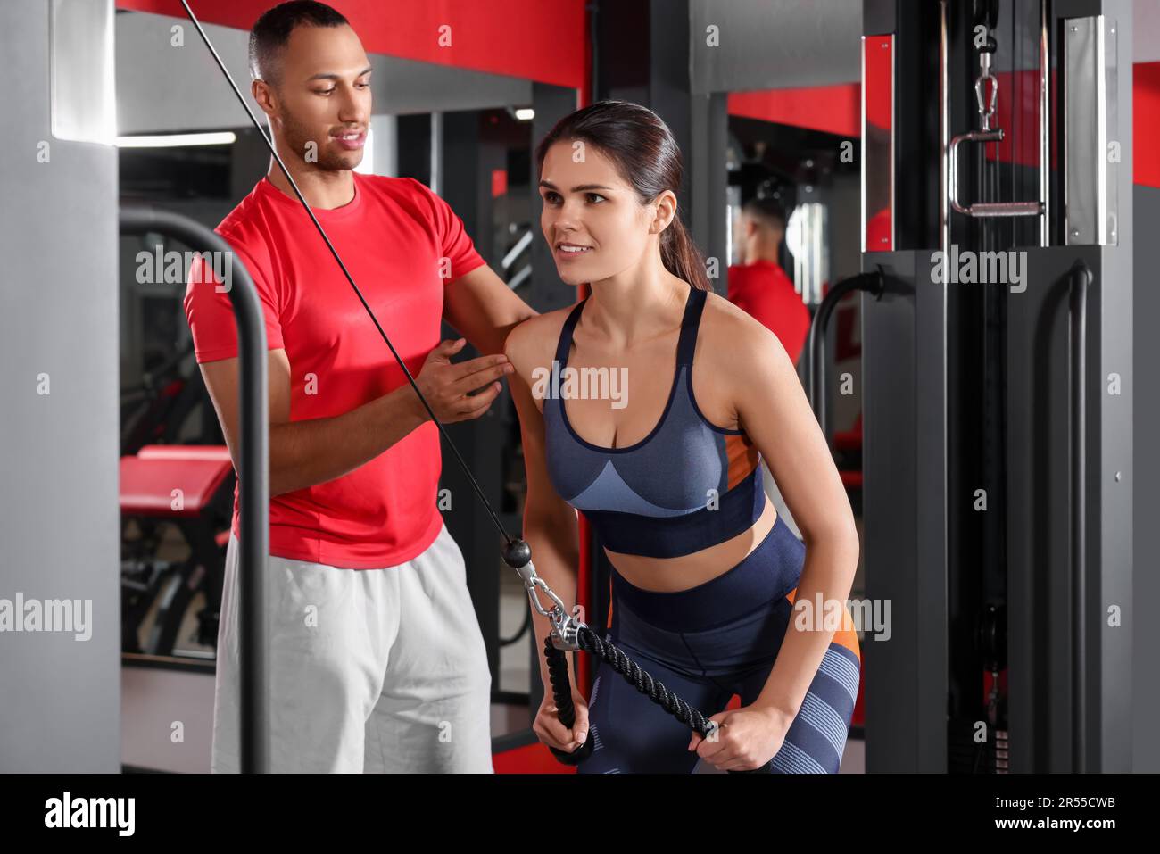 Trainer explaining woman how to do exercise properly in modern gym ...