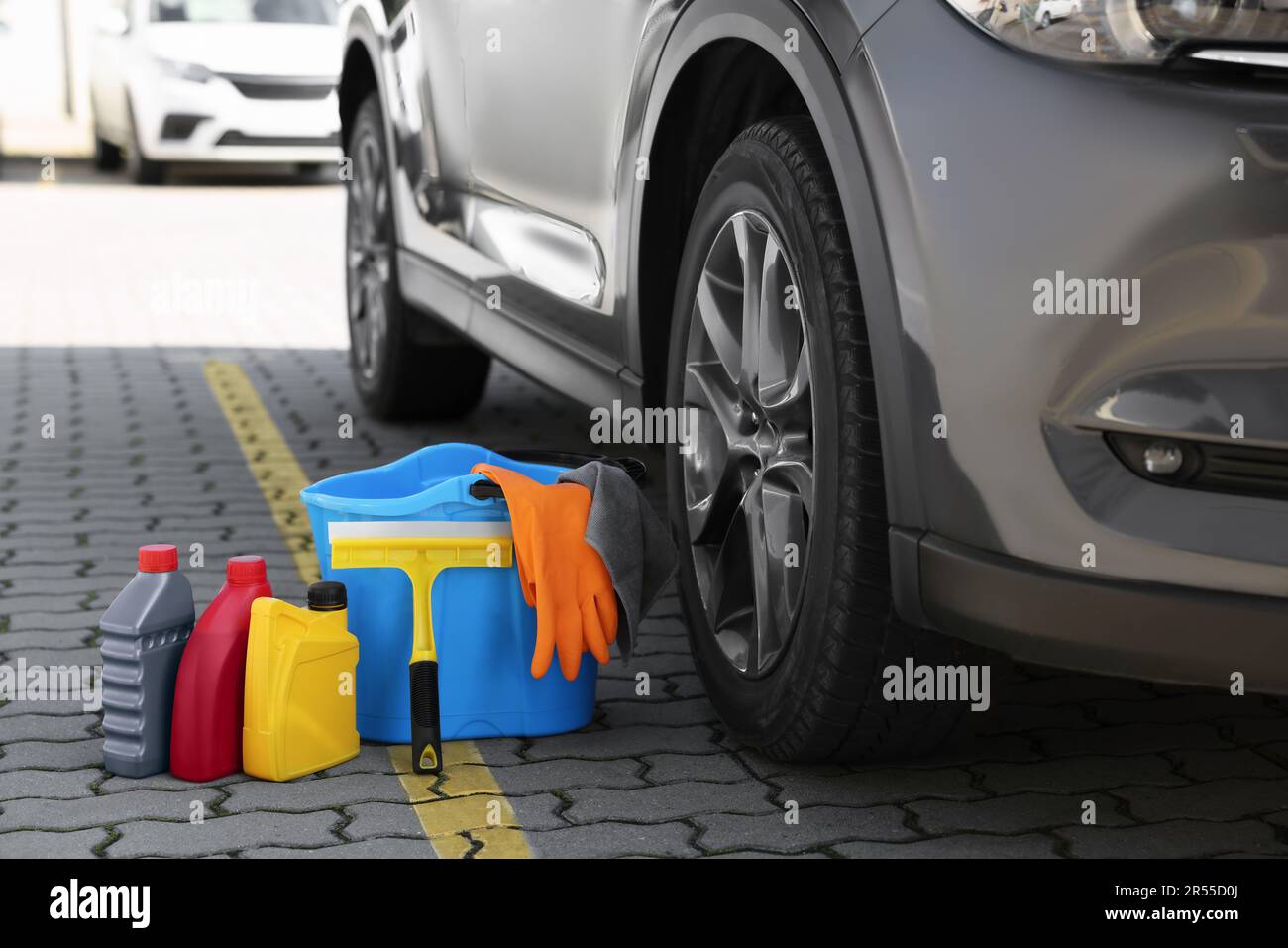 Car cleaning products and bucket near automobile outdoors on sunny day ...