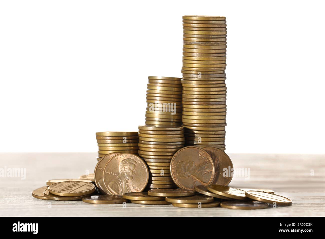 Stack of coins on wooden table against white background Stock Photo - Alamy