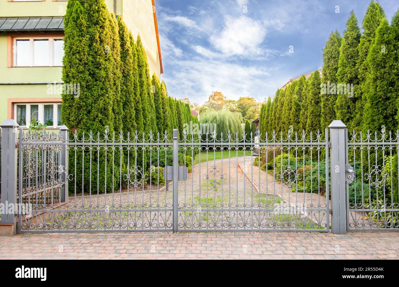 House and trees behind beautiful iron fence outdoors Stock Photo - Alamy