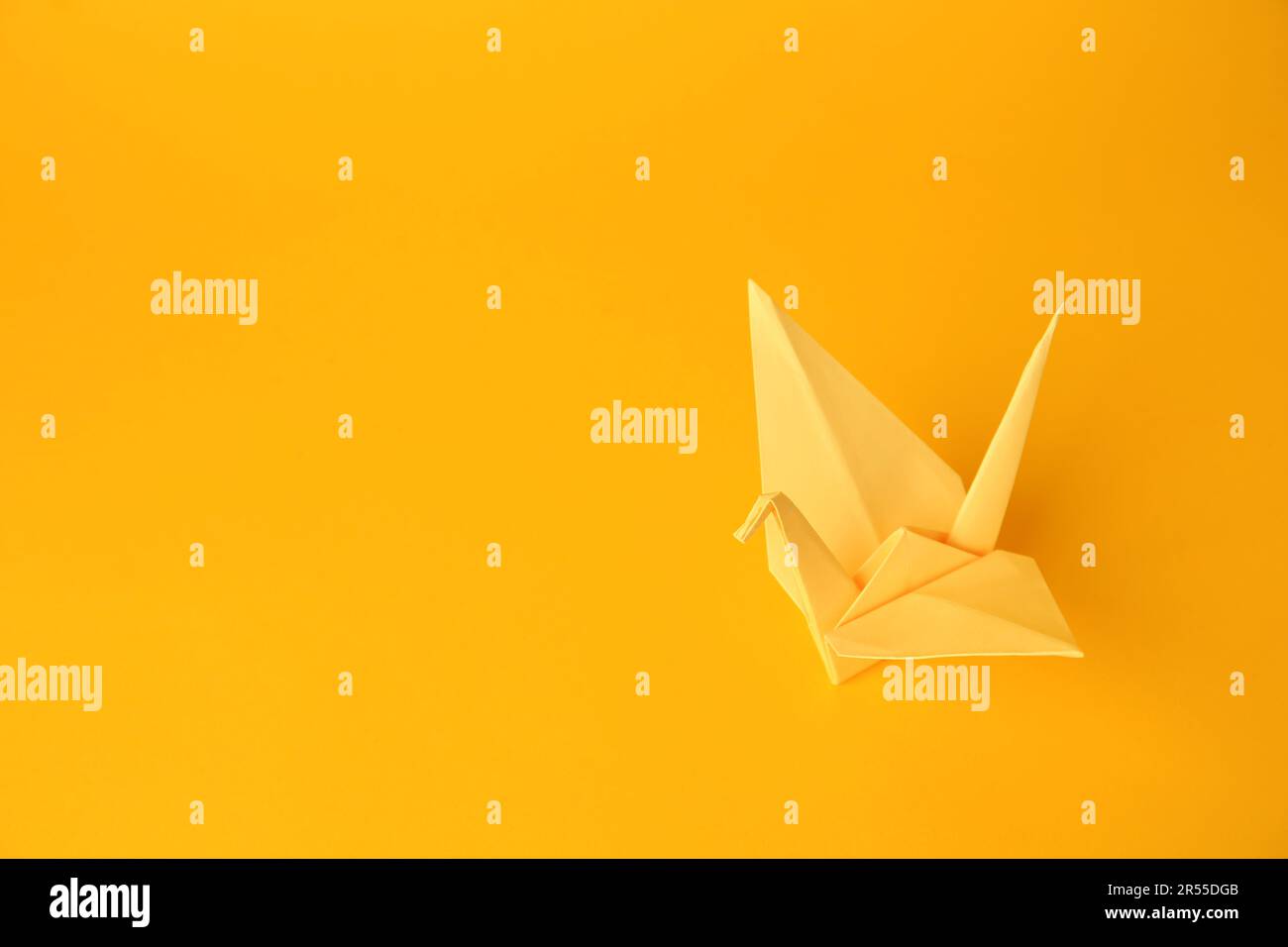 Origami art. Beautiful light yellow paper crane on orange background ...