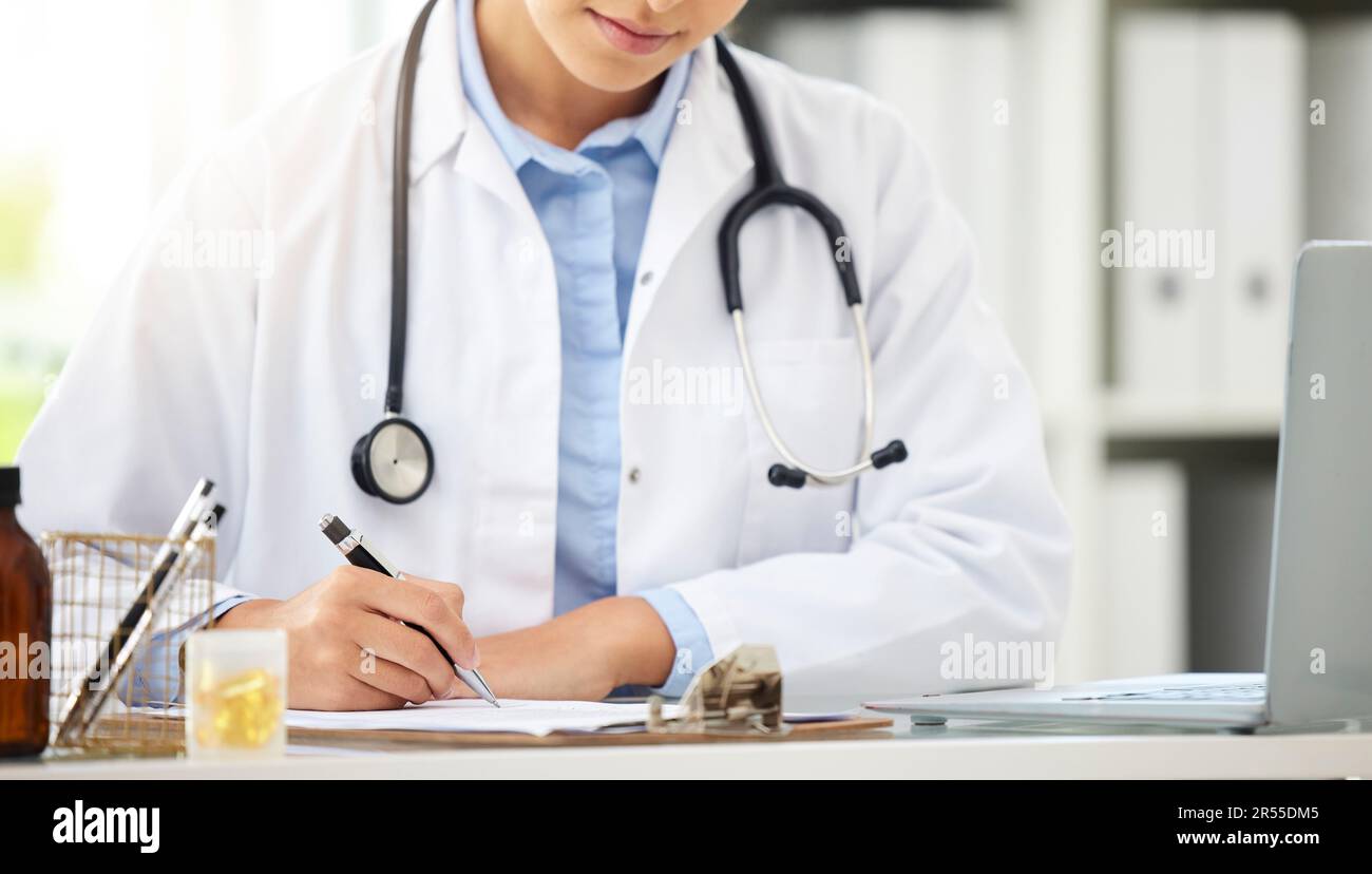 Planning, doctor writing on a clipboard and with laptop at a desk in a ...