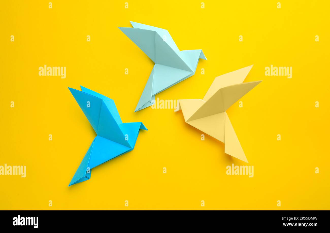 Origami art. Colorful handmade paper birds on yellow background, flat ...