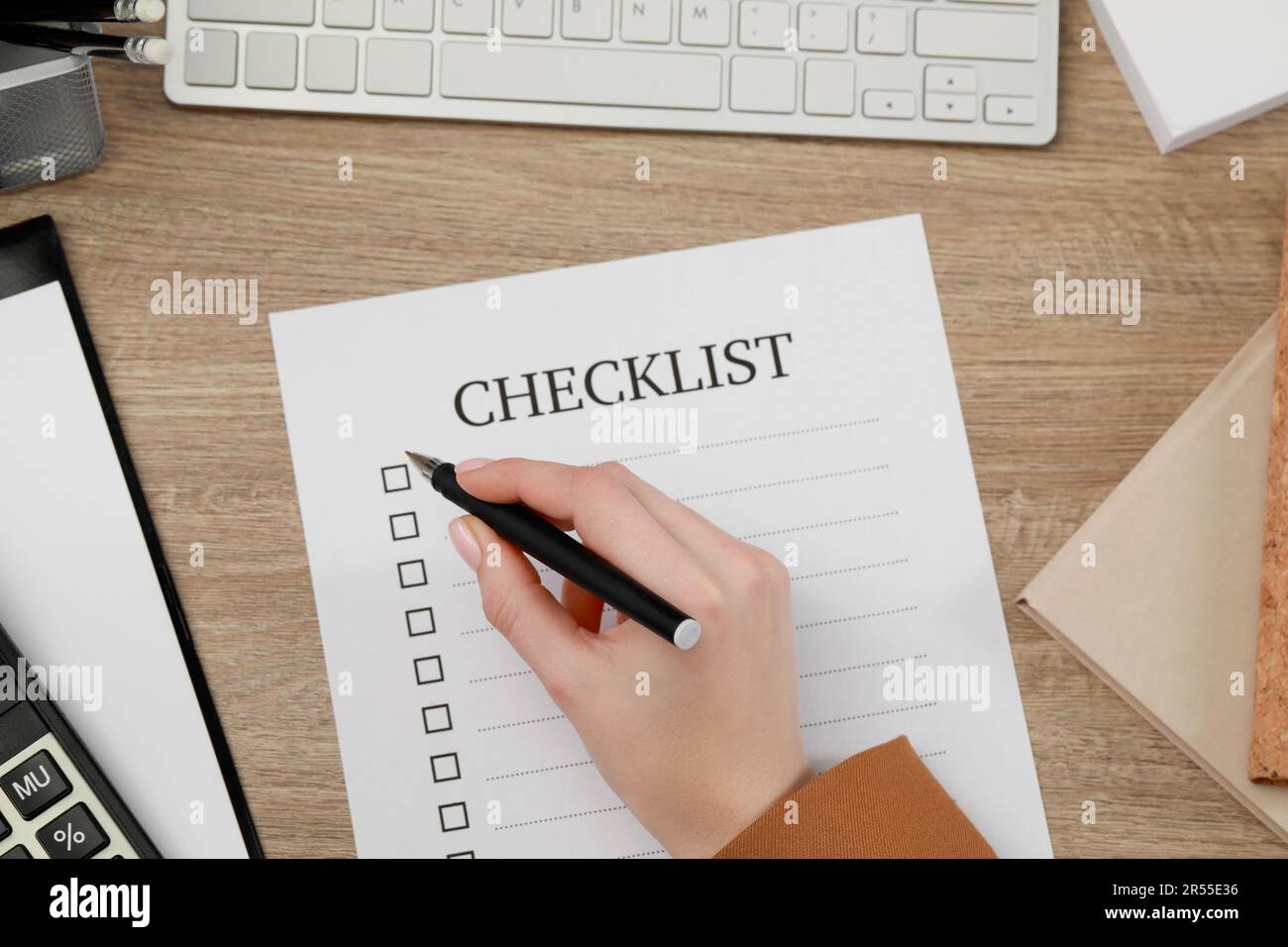 Woman filling Checklist at wooden table, top view Stock Photo - Alamy