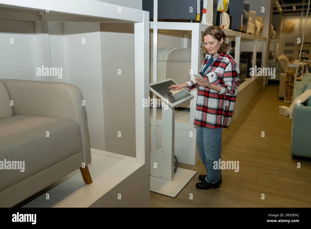 Woman with phone uses self-service kiosk in the shopping mall. High ...