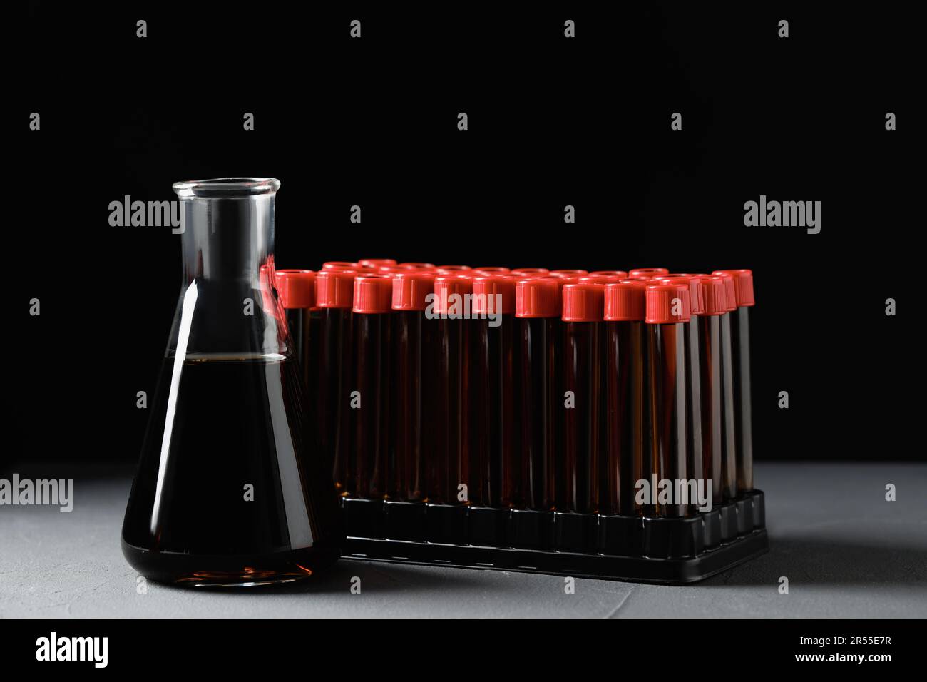 Different laboratory glassware with brown liquid on grey table against ...