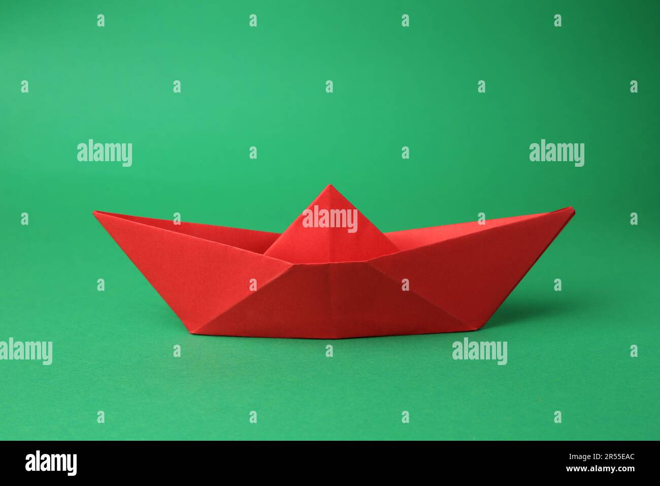 Origami art. Red paper boat on green background Stock Photo - Alamy