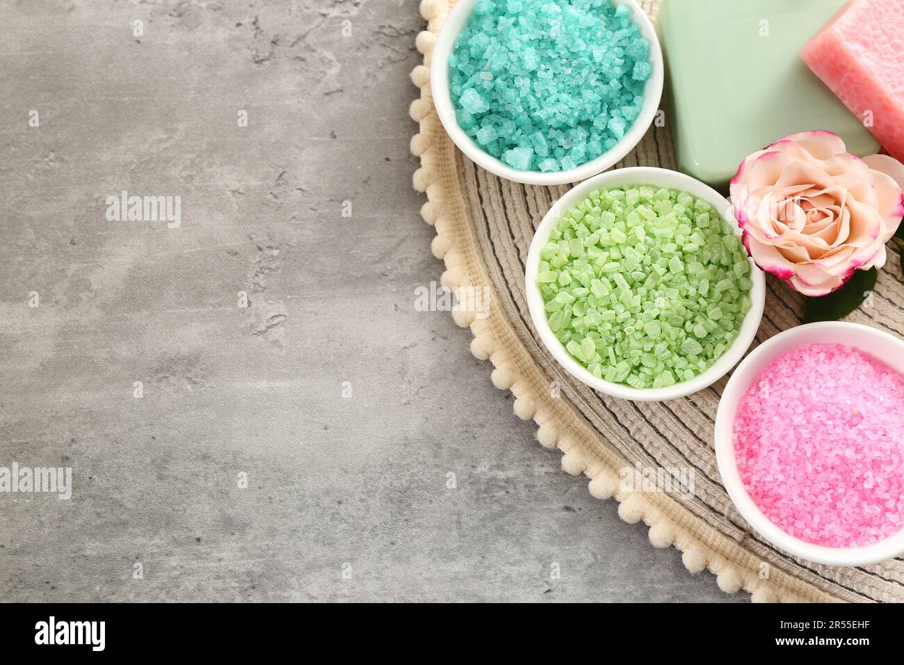 Different types of aromatic sea salt and beautiful flower on grey ...
