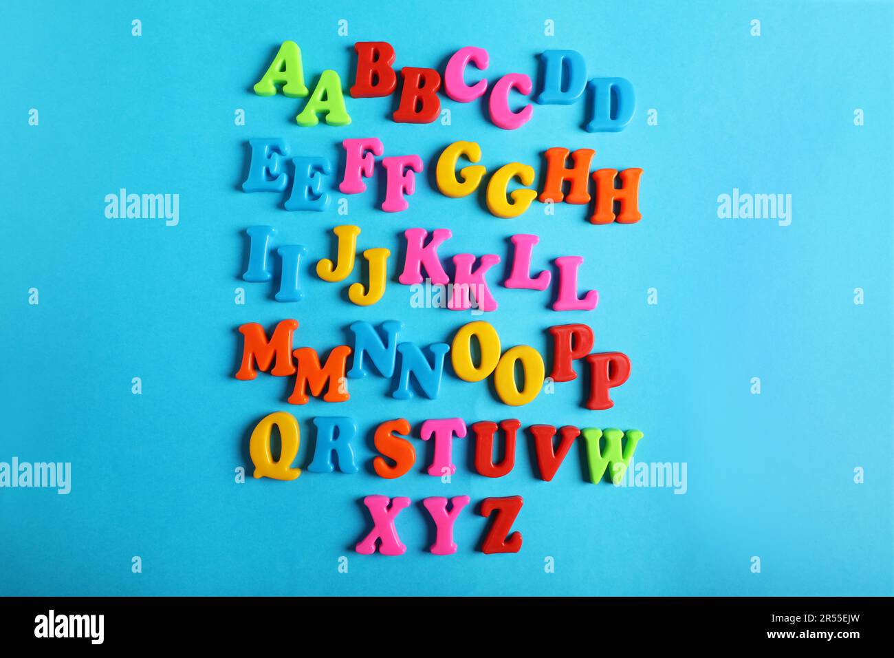 Many colorful magnetic letters on light blue background, flat lay ...