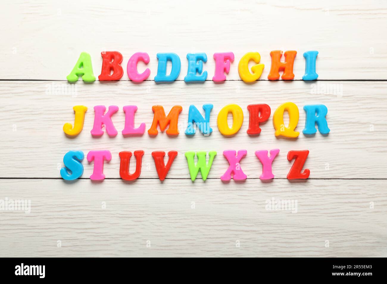 Colorful magnetic letters on white wooden table, flat lay. Alphabetical ...