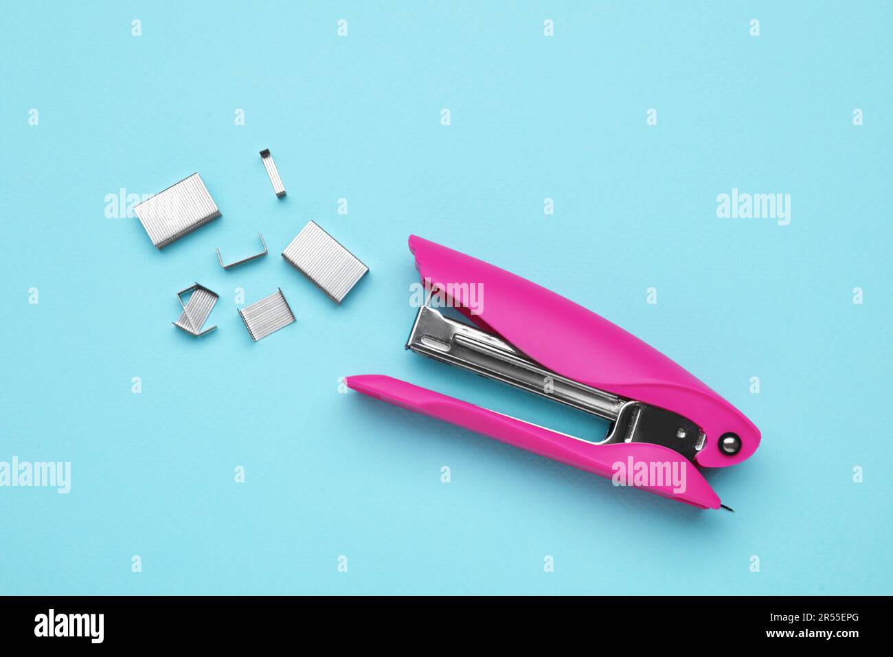 New bright stapler with staples on light blue background, fat lay ...