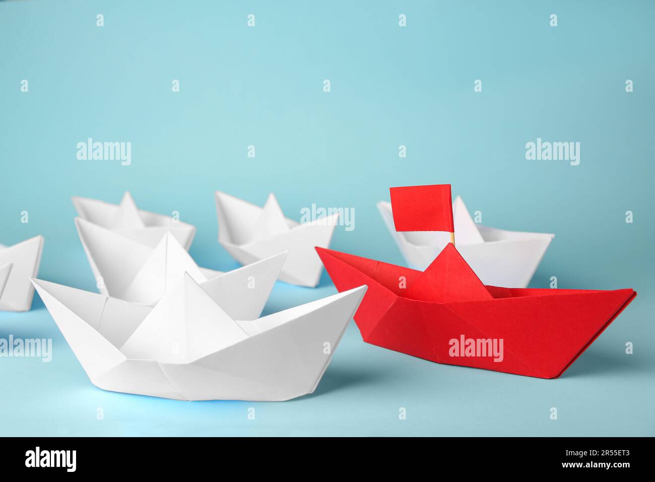 Red paper boat among others on light blue background. Uniqueness ...