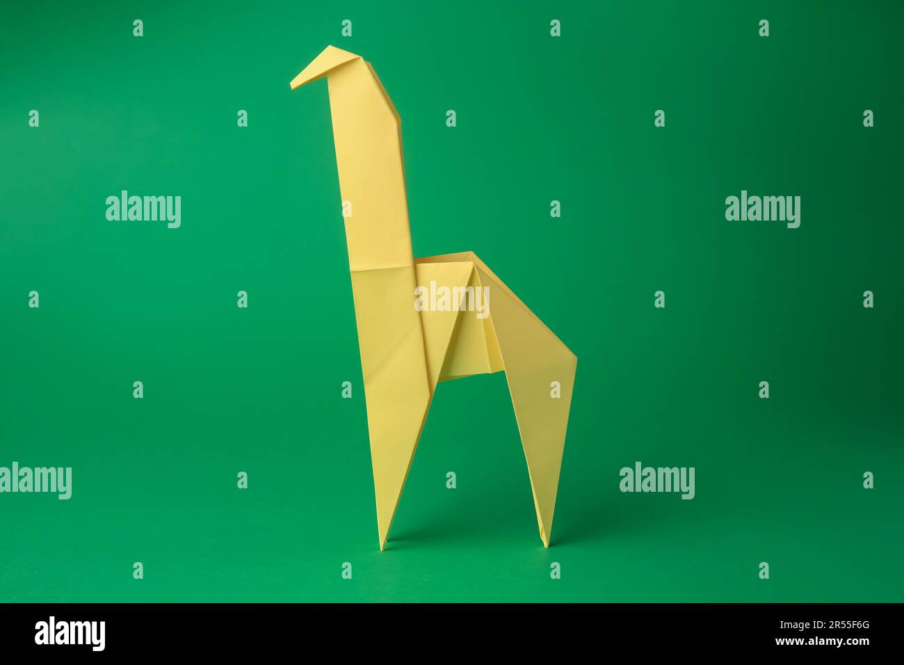 Origami art. Handmade yellow paper giraffe on green background Stock ...
