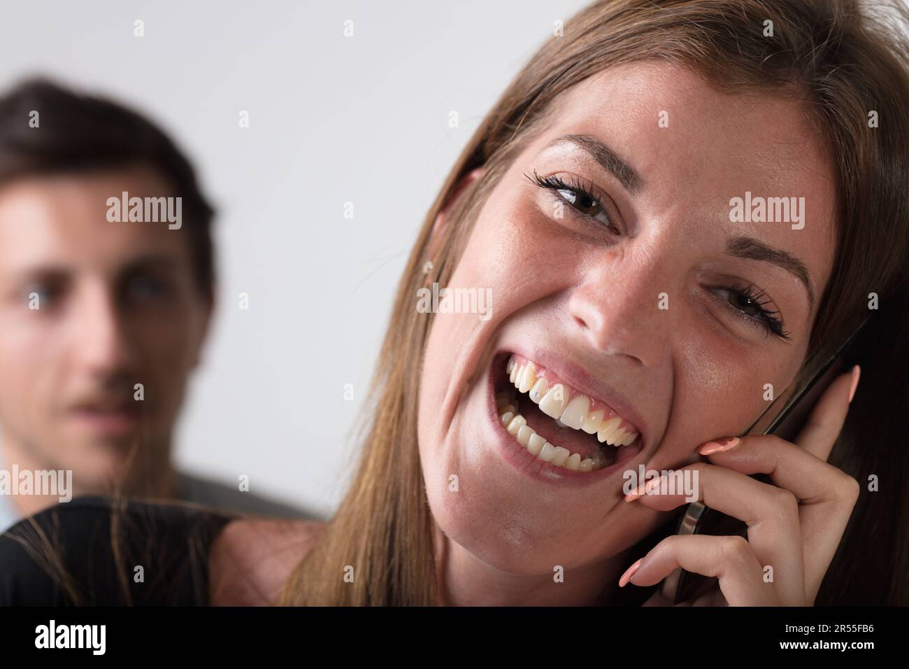 In focus, a woman is engaged on a smartphone call; a suspicious and ...