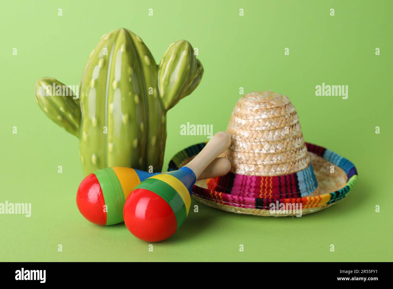 Colorful maracas, toy cactus and sombrero hat on light green background ...