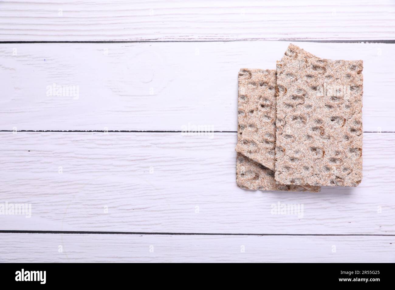 Fresh crunchy crispbreads on white wooden table, top view. Space for ...