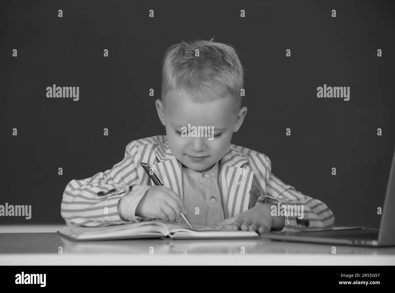 Little schoolboy study in a classroom at elementary school. Kid writing ...
