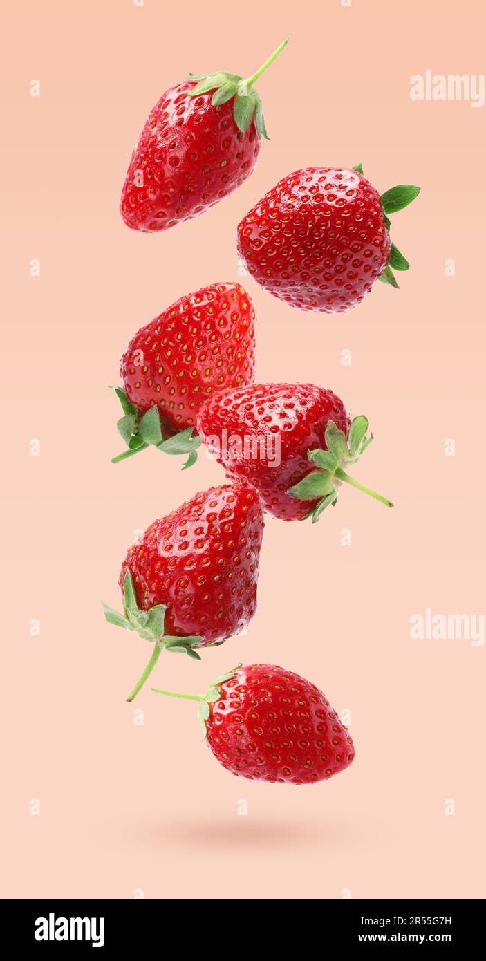 Delicious sweet strawberries falling on pale pink background Stock ...