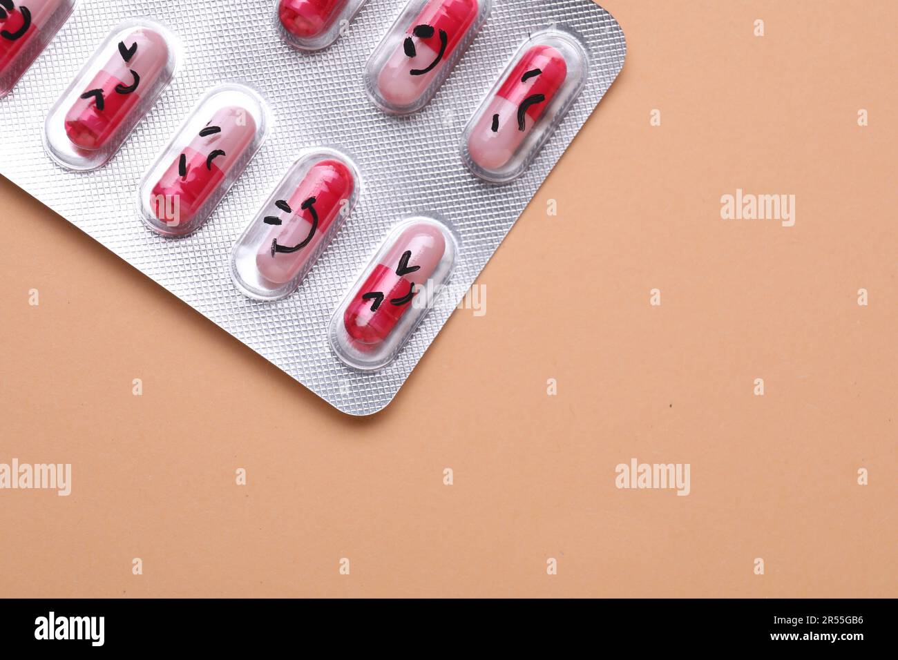 Blister of antidepressant pills with emotional faces on pale orange ...