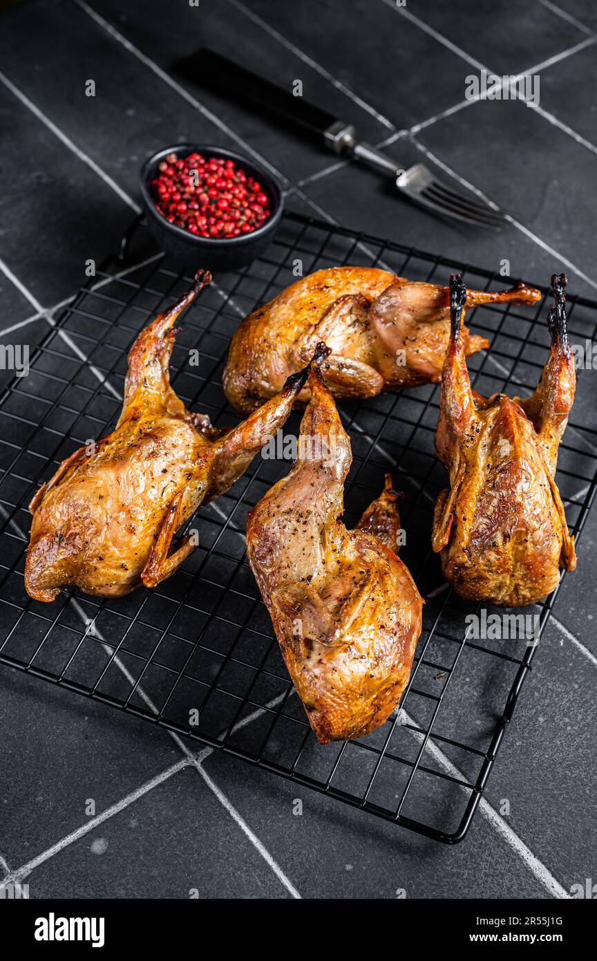 Grilled whole quails with herbs and spices. Black background. Top view ...
