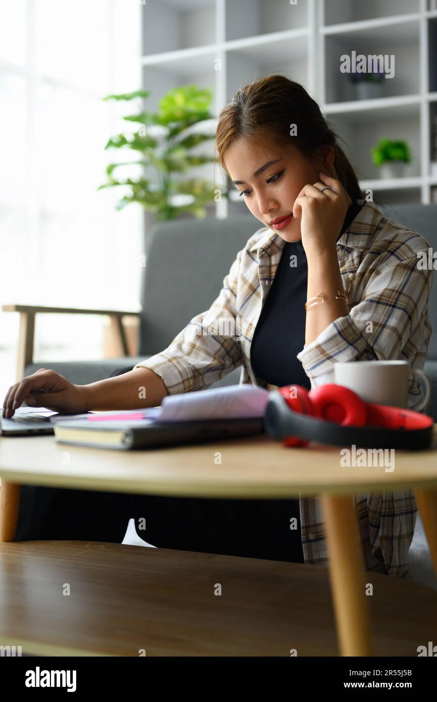 Focused young woman calculating domestic expenses, utility bills at ...