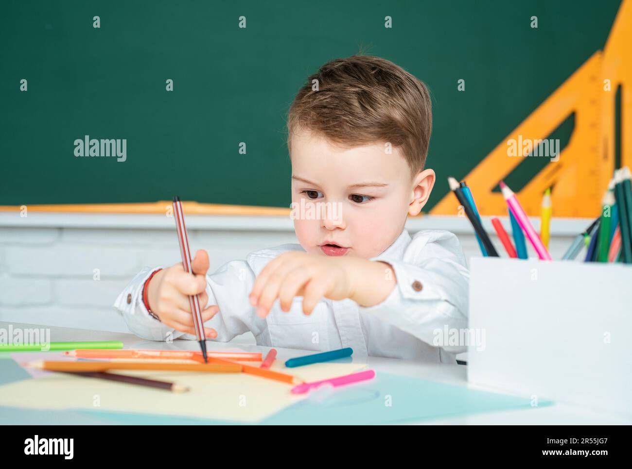 Kid boy writing in classroom. Schoolboy studying homework during her ...