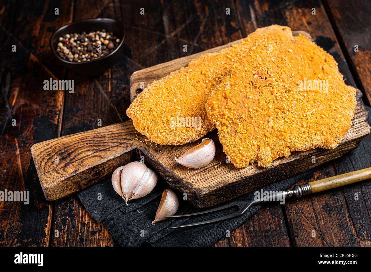Uncooked Wiener schnitzel in breadcrumbs, raw pork meat. Wooden ...