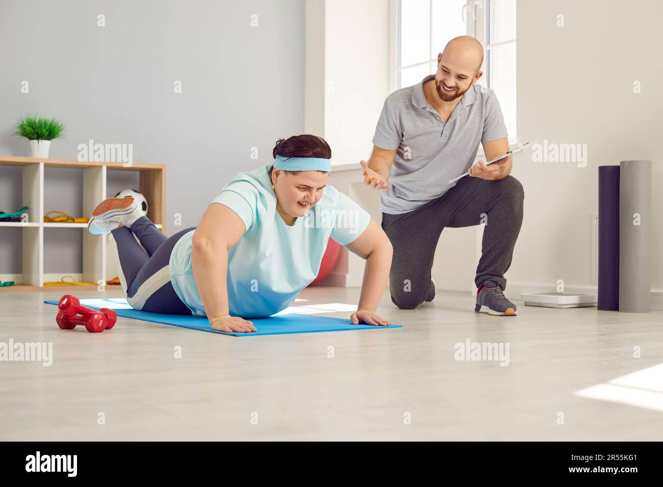 Obese, overweight woman working out with personal trainer in gym Stock ...