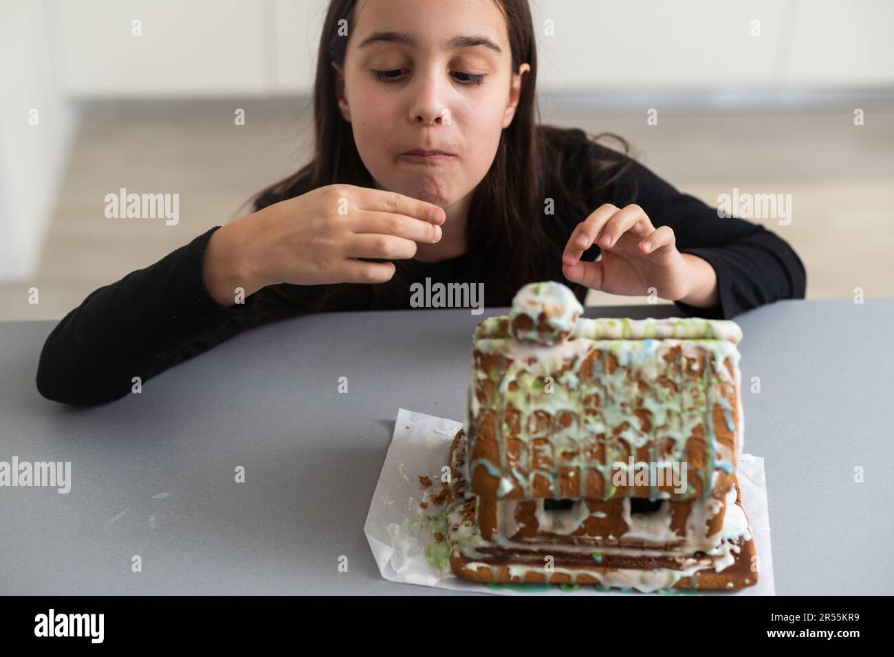 A teenage girl is eating a gingerbread house Stock Photo - Alamy
