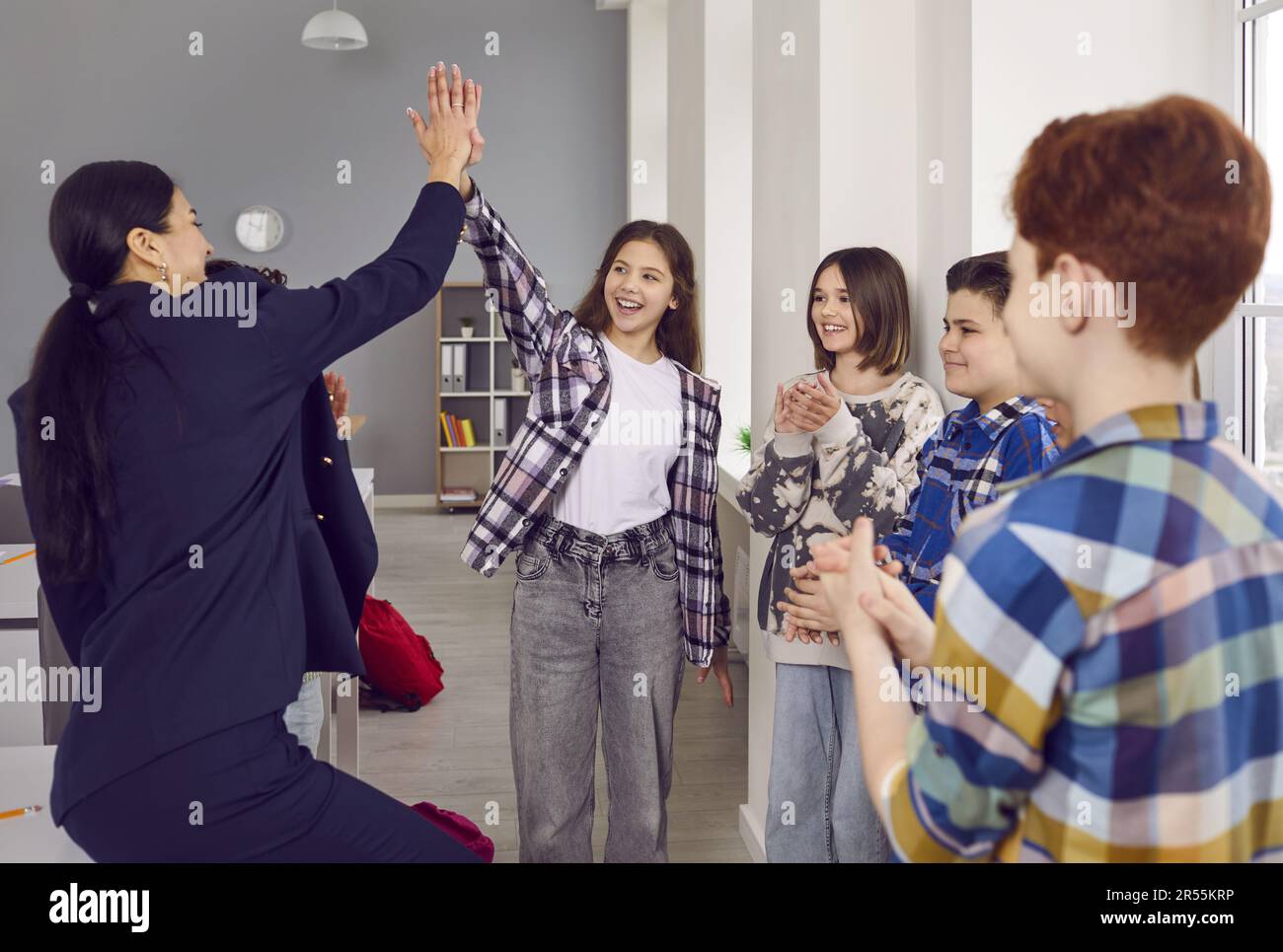 Teacher and schoolchildren giving high fives to each other after summer ...