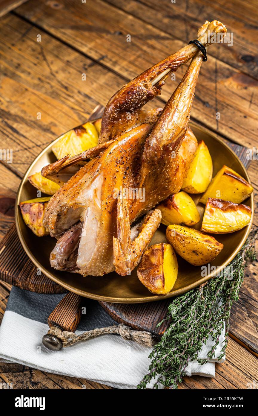 Roasted guinea fowl with herbs and potato, cooked farm eco bird. Wooden ...