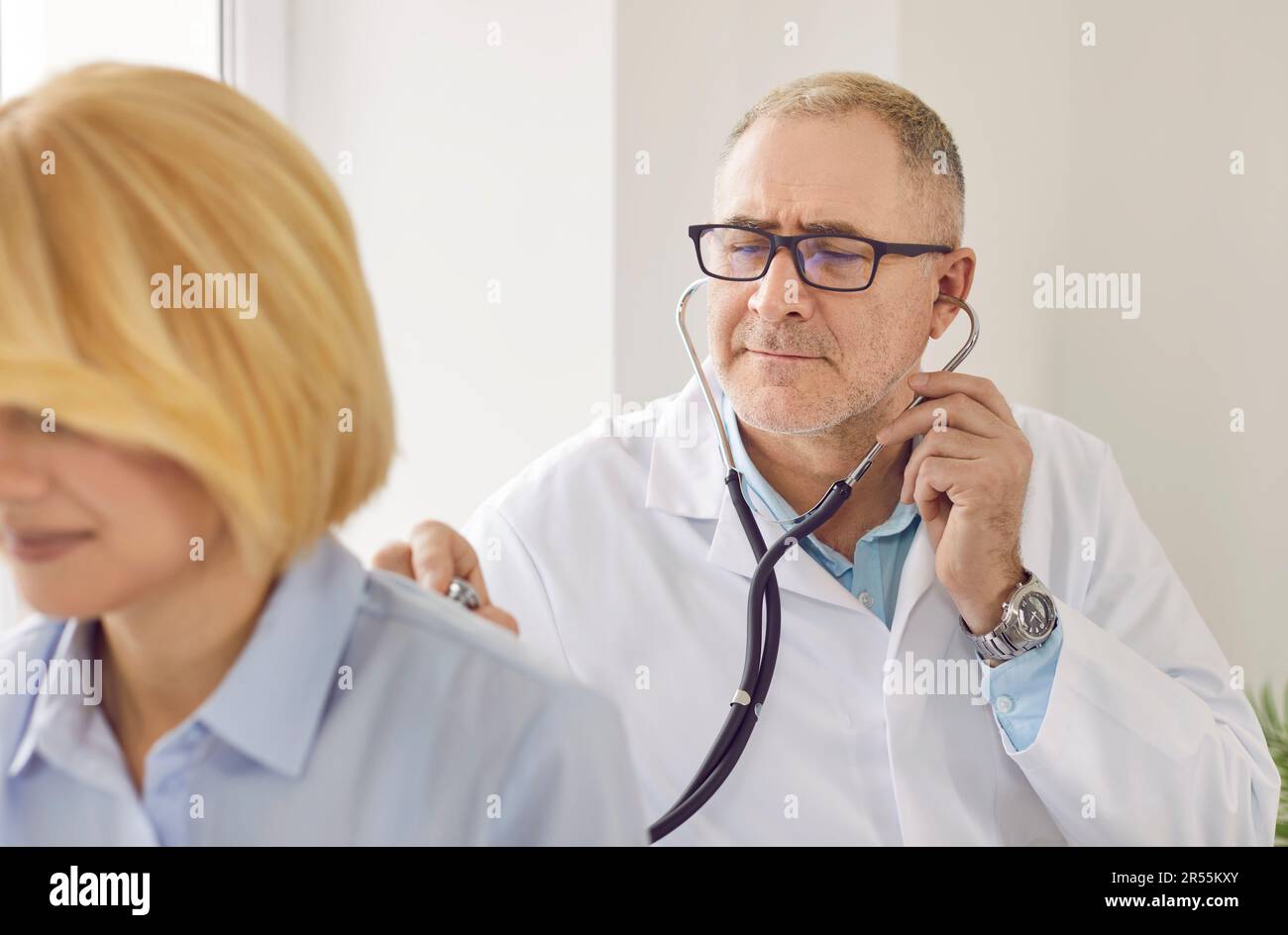 Senior male doctor using stethoscope during medical examination of ...