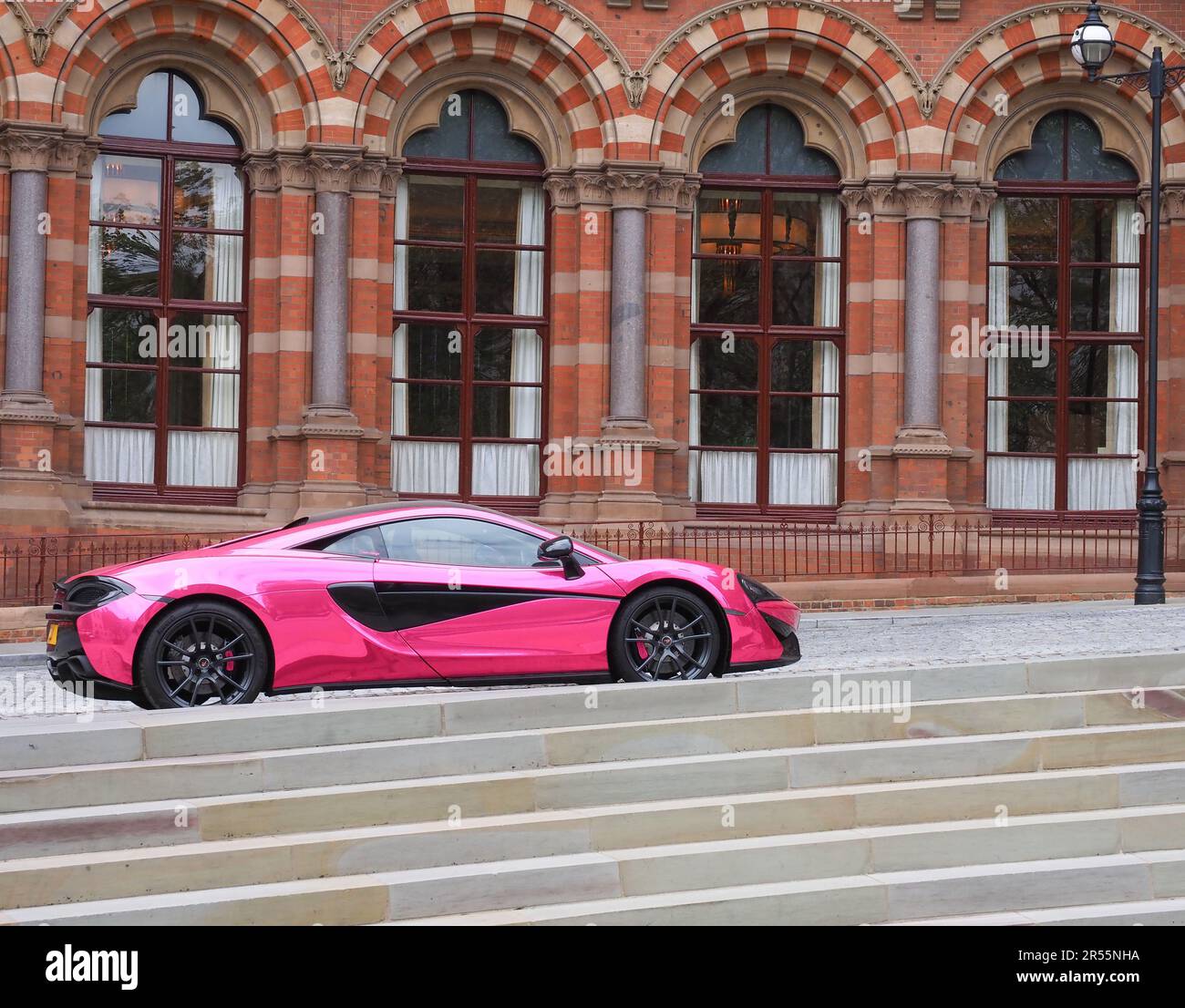 A metallic pink McLaren supercar outside an elegant building Stock ...