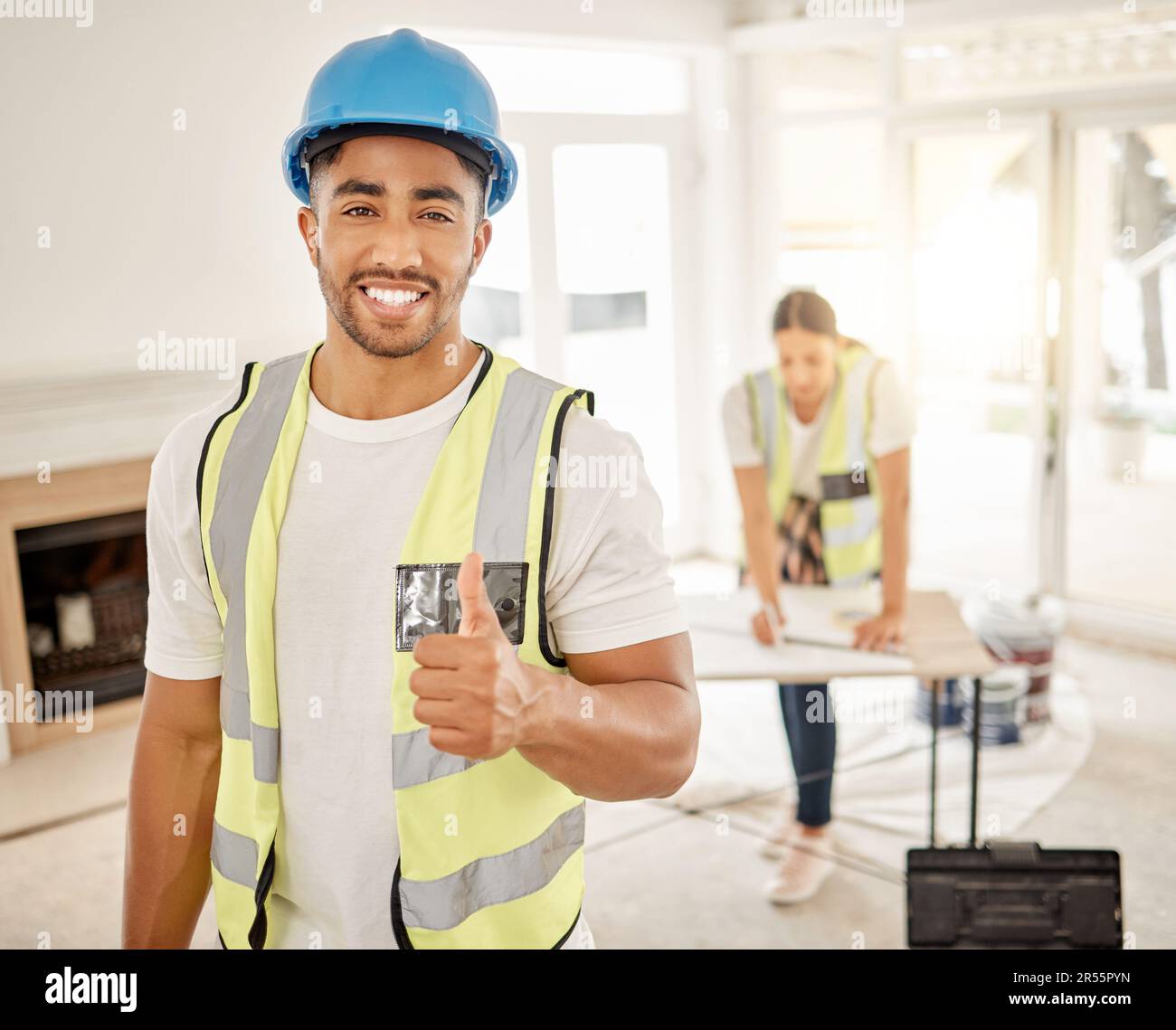 Portrait of man, construction and home renovation with thumbs up, helmet and smile in apartment ...