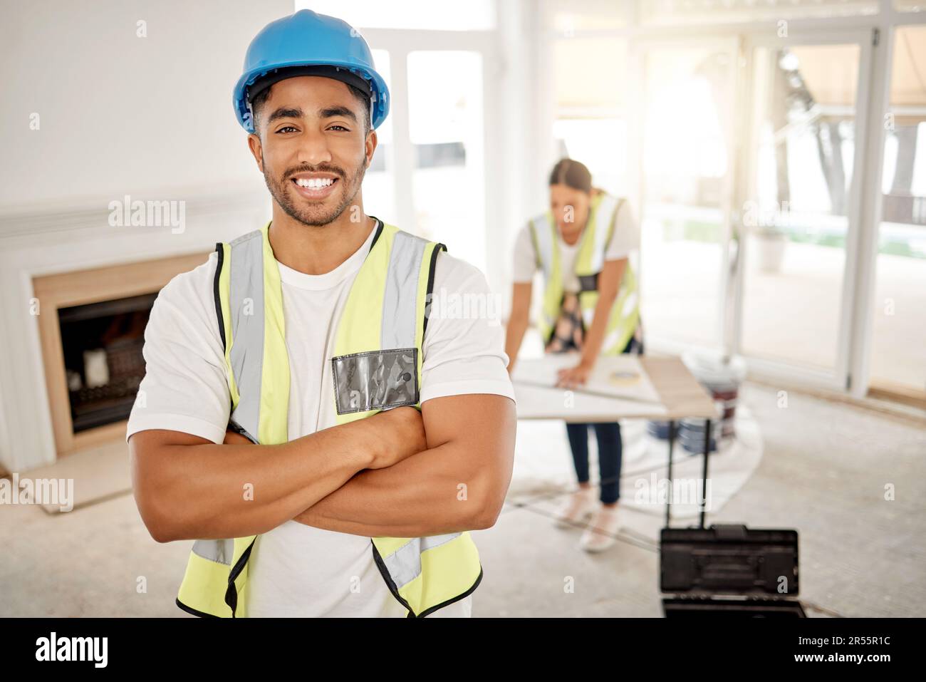 Portrait of man, construction and home renovation with arms crossed, helmet and smile in ...