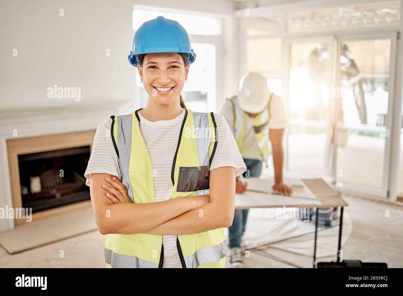 Portrait of woman, construction and home renovation with arms crossed, helmet and smile in ...