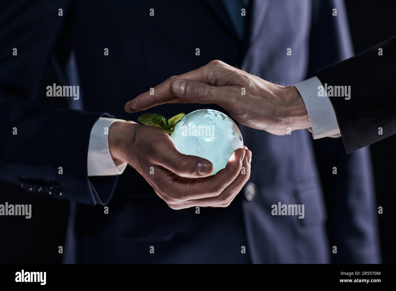 Businessman in a suit holding a glass globe with a world map closeup ...