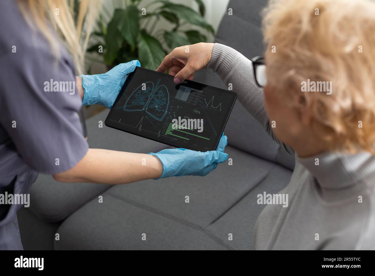 Serious GP doctor showing tablet screen to old 70s female patient ...