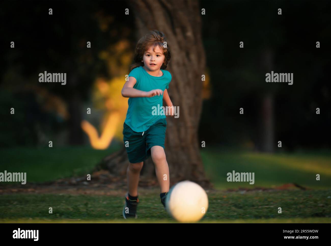 Boy football player kicking football on the sports field. Active kids ...