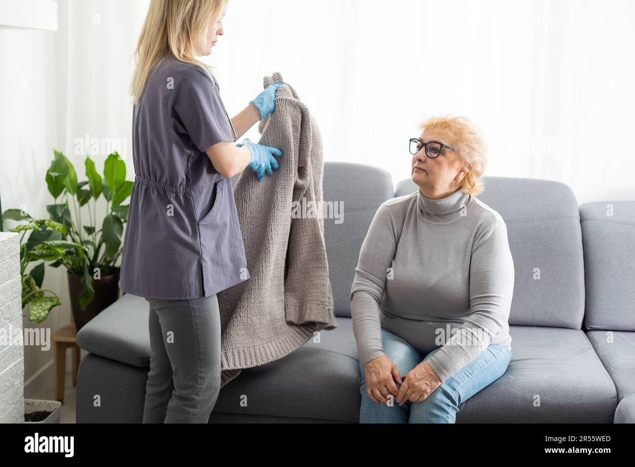 Caring young nurse doctor carer helping holding hands of happy disabled ...
